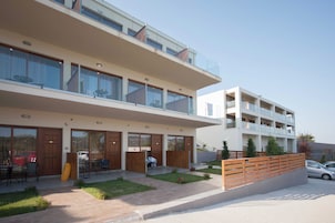 Um edifício residencial moderno com várias andares, varandas, janelas amplas e um jardim bem cuidado.