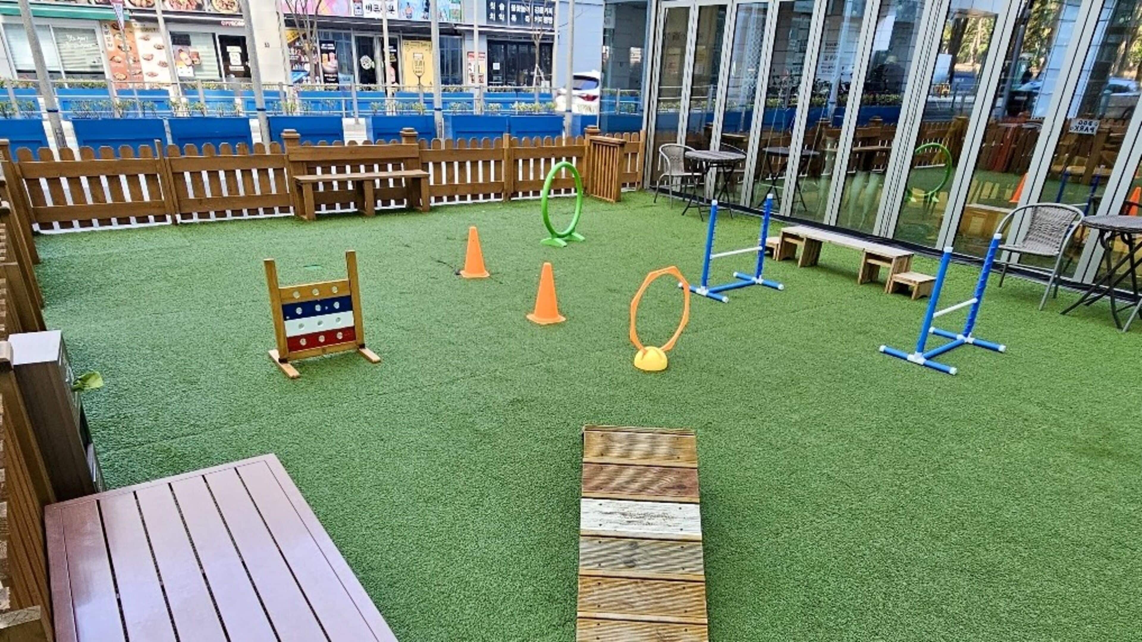 Espaço de recreação ao ar livre com grama sintética, brinquedos de madeira e assentos.