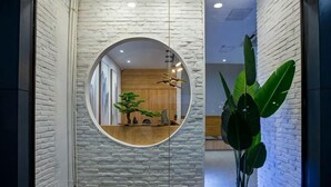 Um quarto com um espelho redondo, uma porta de madeira e uma planta grande.