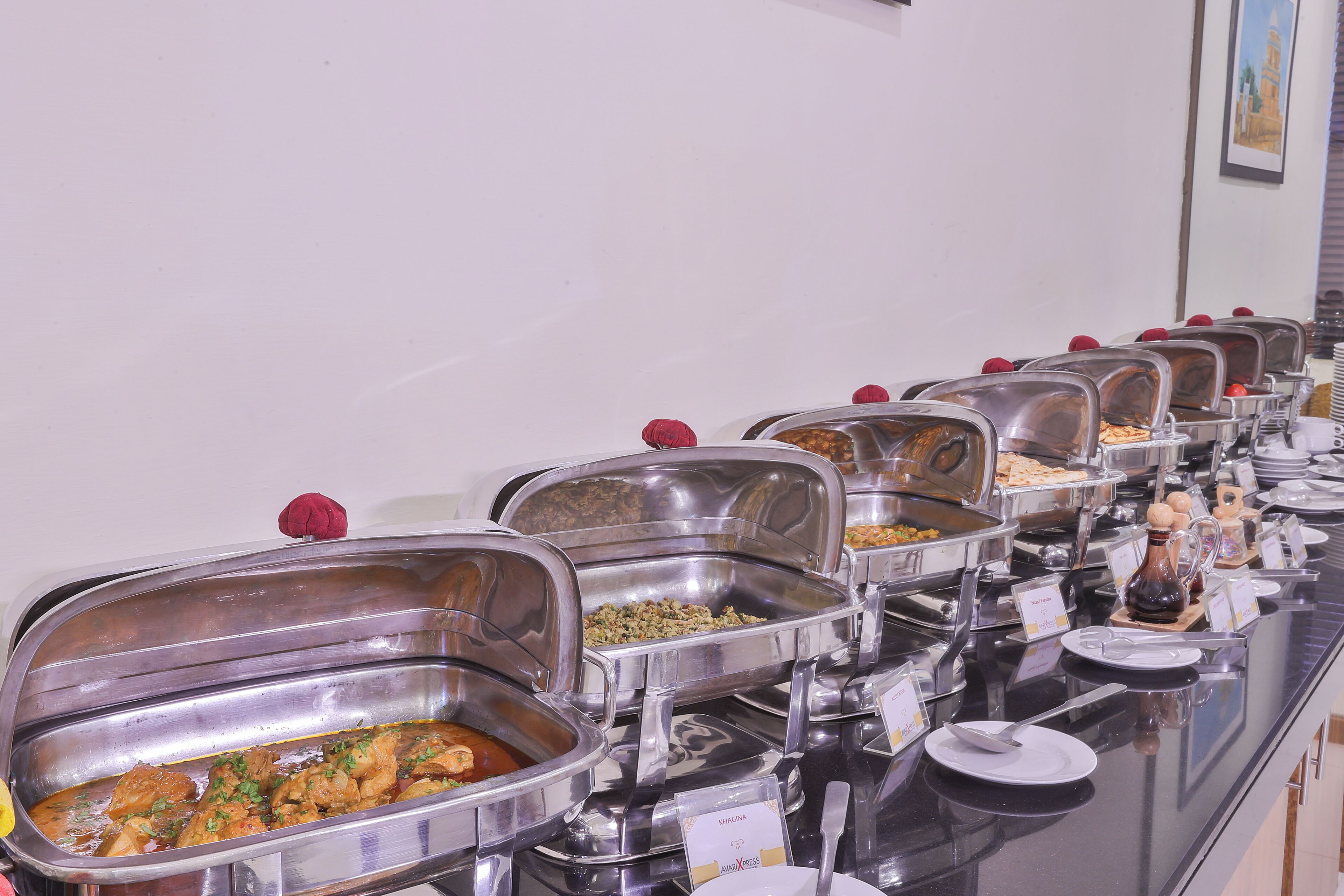 Buffet com diversos recipientes de comida e utensílios.