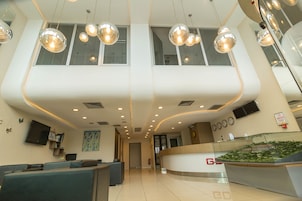 Um lobby moderno de hotel com balcão de recepção, área de estar e iluminação decorativa.