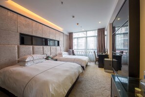 Quarto de hotel com duas camas, uma escrivaninha, uma cadeira e uma janela grande.