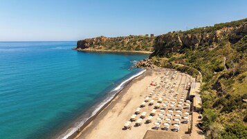 Na praia, praia de areia negra, espreguiçadeiras, guarda-sóis de praia 