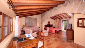 Quarto aconchegante com escrivaninha de madeira, cama, sofá e parede de pedra.