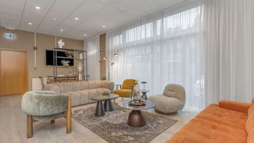 Uma sala de estar moderna com um sofá de canto, poltronas, uma mesa de centro e uma área de jantar com mesa e cadeiras.