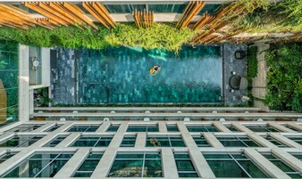 Uma piscina no terraço com água azul cristalina, rodeada por vegetação e arquitetura moderna.