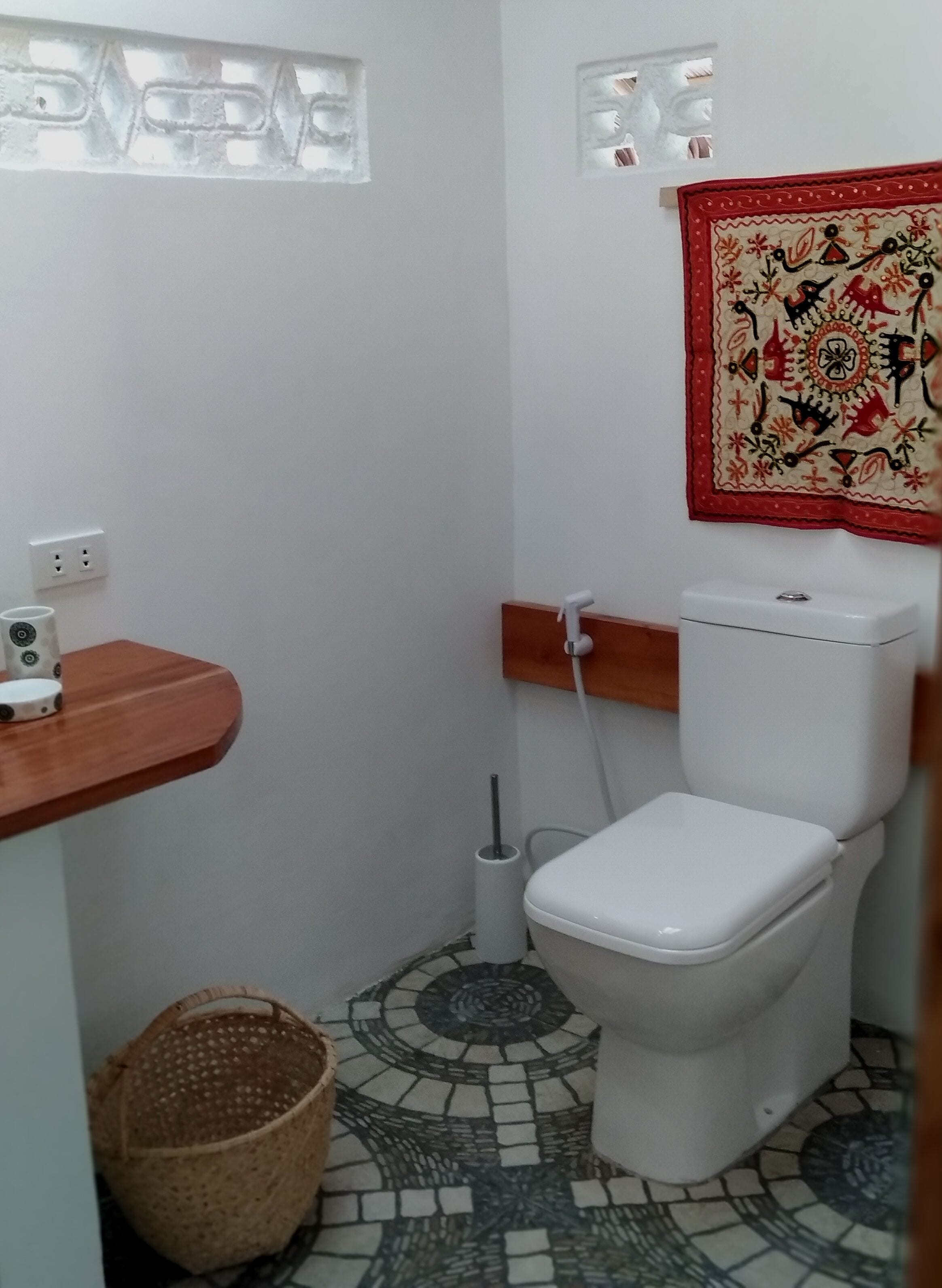 Uma casa de banho pequena com casa de banho, lavatório, um ornamento na parede e chão estampado.