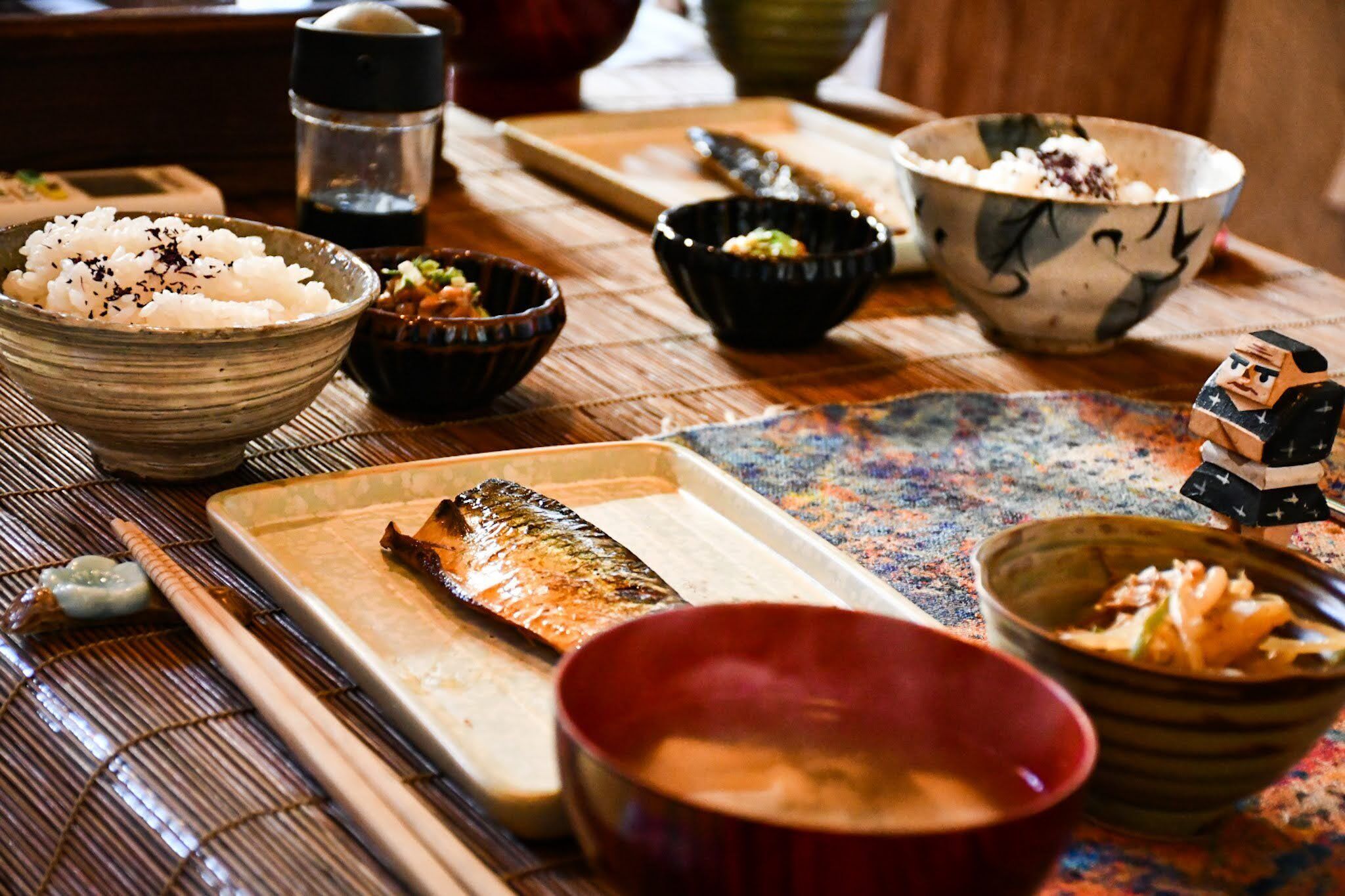 Uma mesa de jantar com diversos pratos, incluindo arroz, peixe e tigelas de sopa.