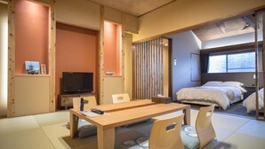 Um quarto tradicional japonês com tatames, uma mesa de madeira baixa e uma cama com futon.