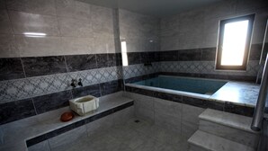 Casa de banho com chão de mármore, uma banheira e uma janela.