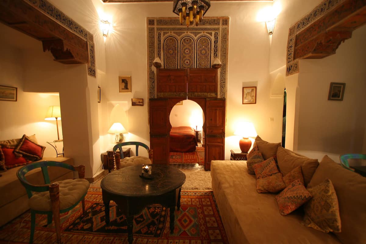 Uma sala de estar tradicional com sofá, poltronas, mesa de centro e um tapete estampado.