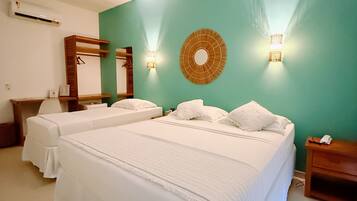 Quarto de hotel com duas camas, um espelho, luminária na parede e ventoinha no teto.