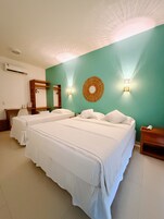 Quarto de hotel com duas camas, um espelho, luminária na parede e ventoinha no teto.