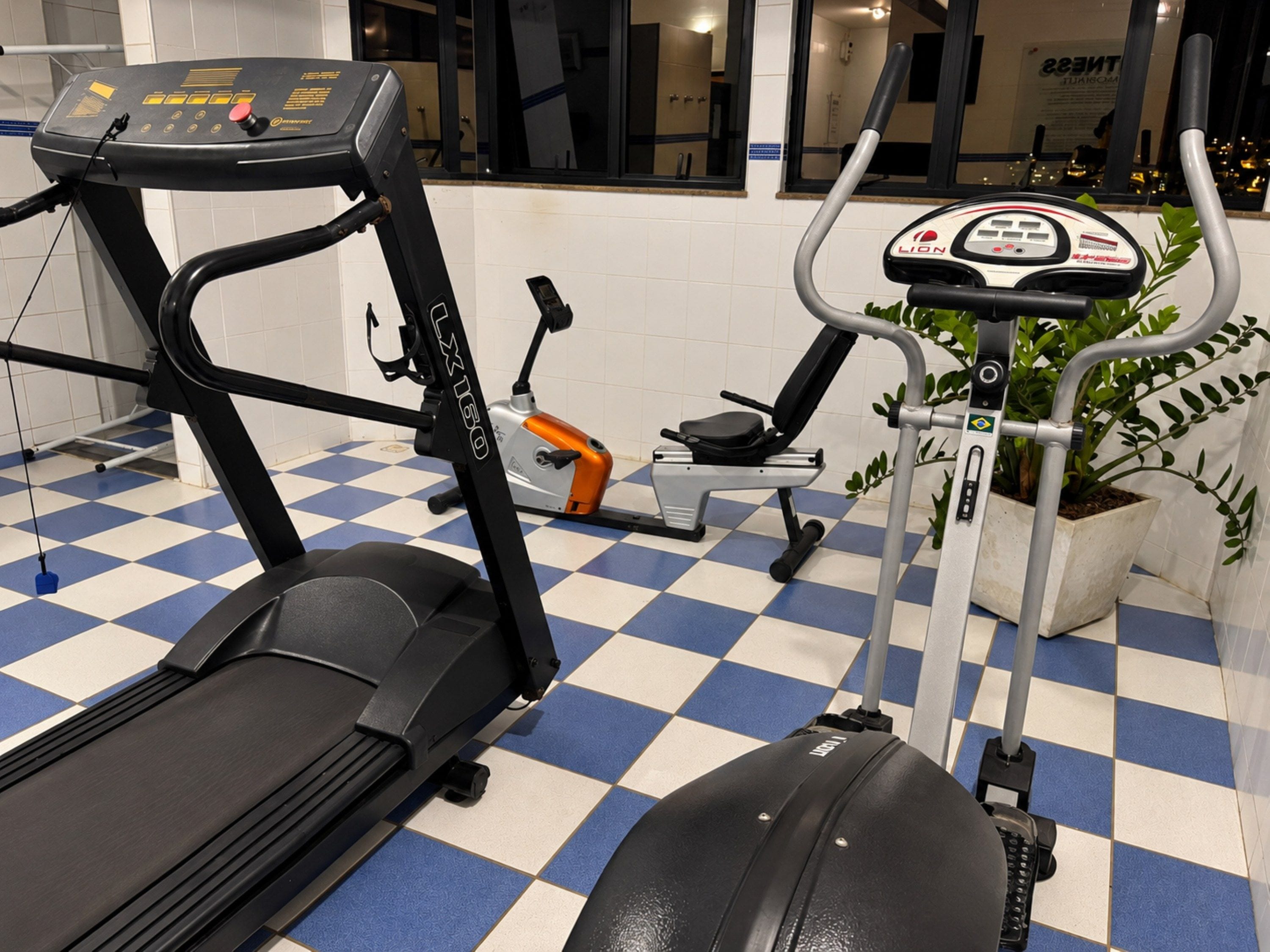 Academia com equipamentos de ginástica, incluindo esteira e elíptico.
