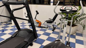 Academia com equipamentos de ginástica, incluindo esteira e elíptico.