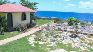 Uma casa pequena com telhado vermelho e vista para o oceano.