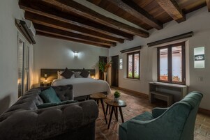 Quarto com cama, sofá, mesinha e janela com vista.