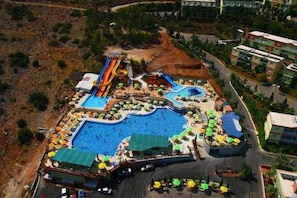 Vista aérea de um resort com várias piscinas, um tobogã e espreguiçadeiras.