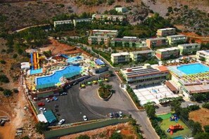 Vista aérea de um resort com vários edifícios, uma piscina e estacionamento.