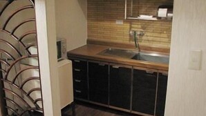 Cozinha compacta com bancada de madeira, pia e micro-ondas.