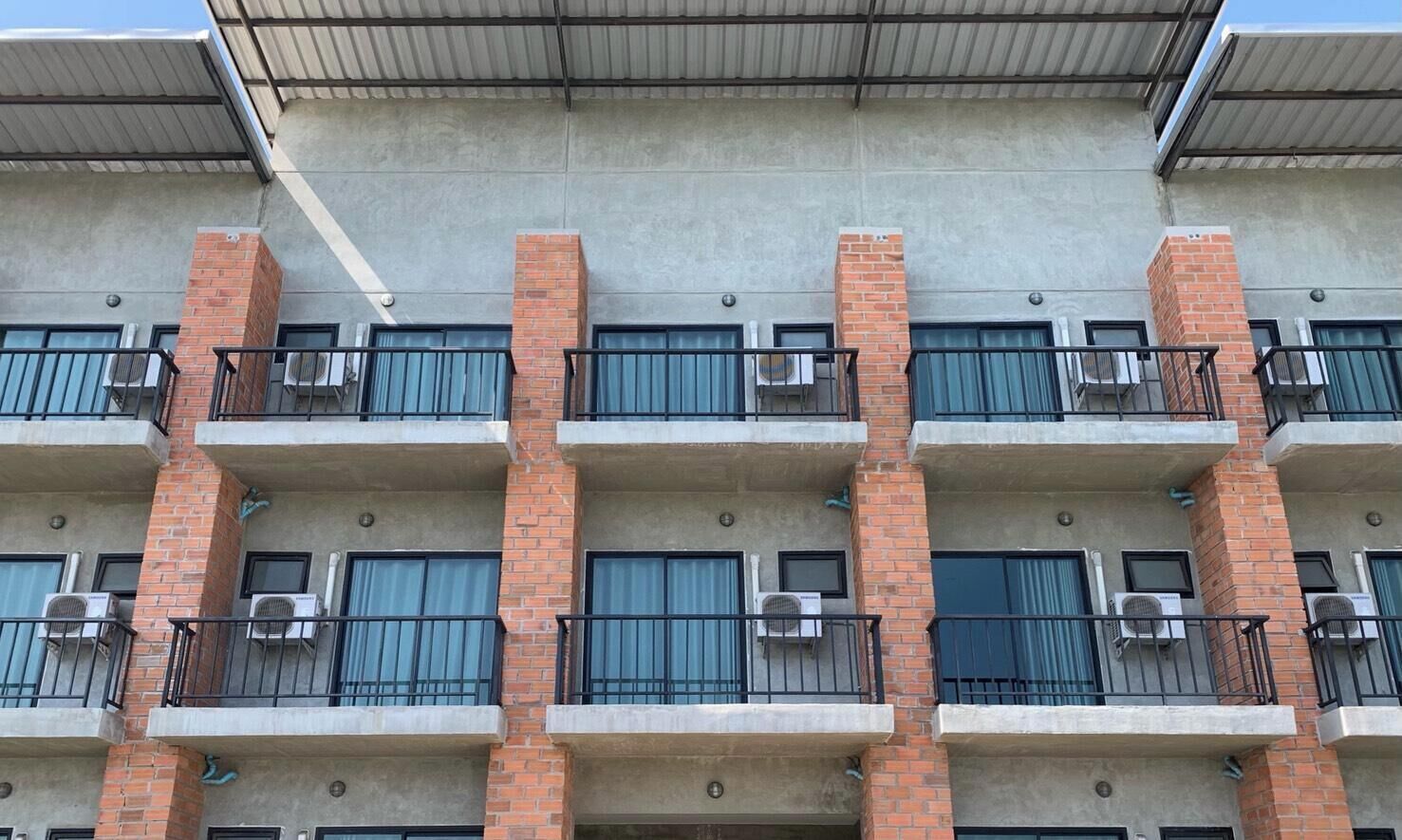 Um edifício com várias andares, varandas, aparelhos de ar condicionado e um telhado plano.