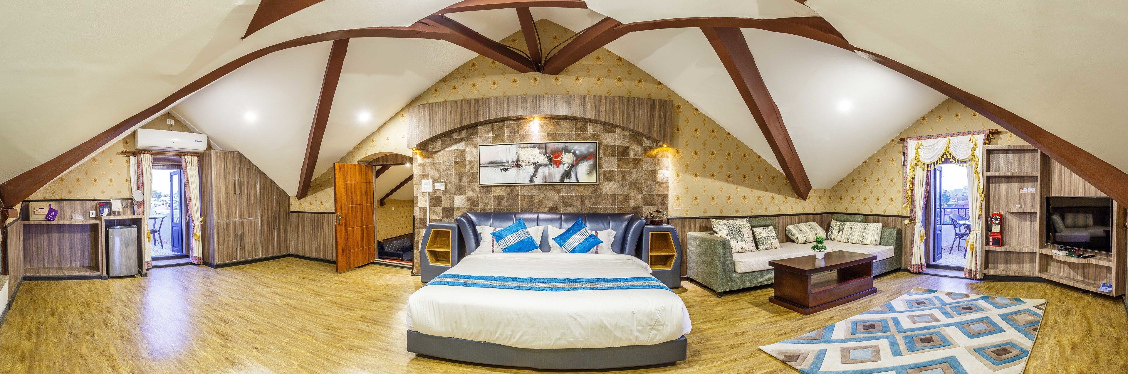 Um quarto espaçoso no sótão, com uma cama grande, um sofá e uma televisão.