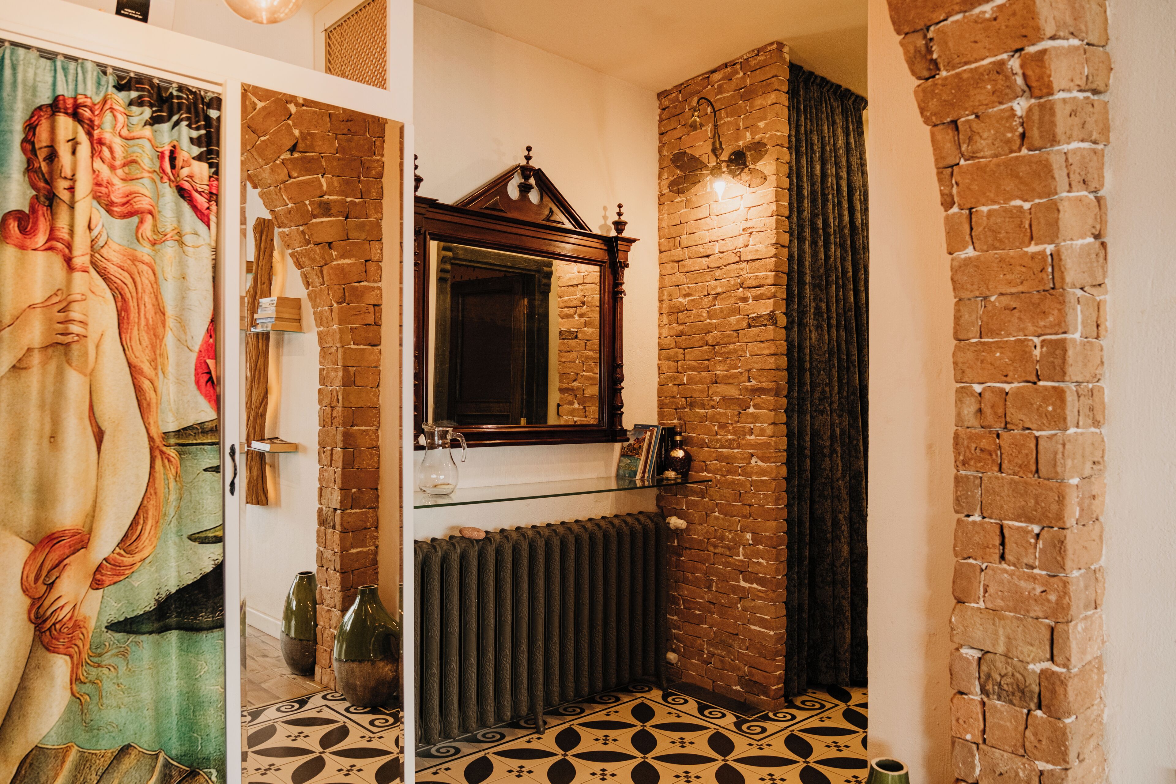 Casa de banho com chão em mosaico, parede de tijolo, espelho e radiador.