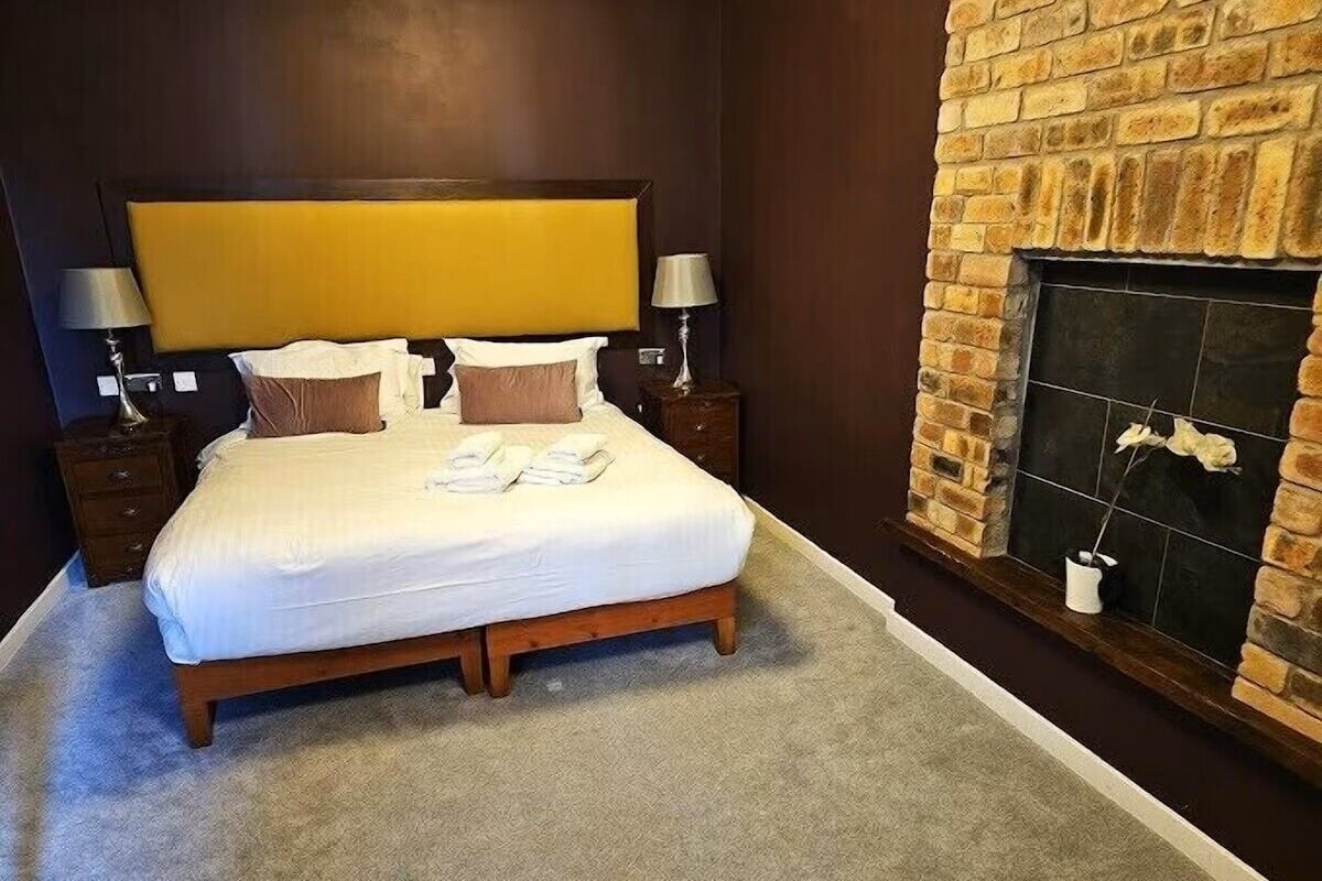 Quarto com uma cama grande, uma lareira e duas mesas de cabeceira com luminárias.