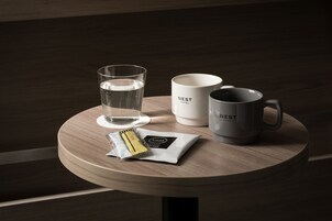 Uma mesa de madeira redonda com um copo de água, uma caneca branca com a inscrição 