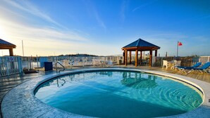 Piscina com um gazebo, cadeiras de espreguiçadeira e área de deck cercada.