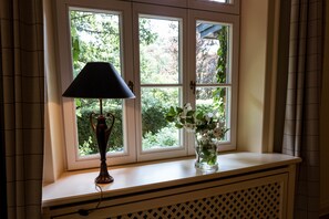 Uma janela com uma luminária e um vaso de flores em um parapeito branco.