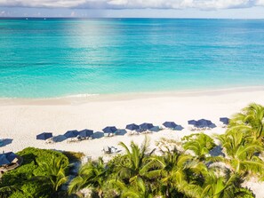Na praia, praia de areia branca, espreguiçadeiras, guarda-sóis de praia 