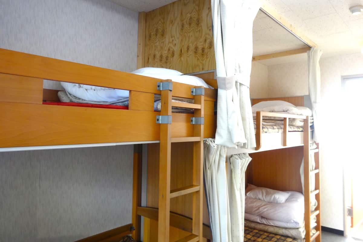 Quarto com beliche, escada de madeira e dossel.