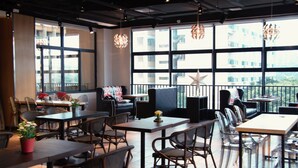 Um restaurante moderno com grandes janelas, mesas e cadeiras de madeira.