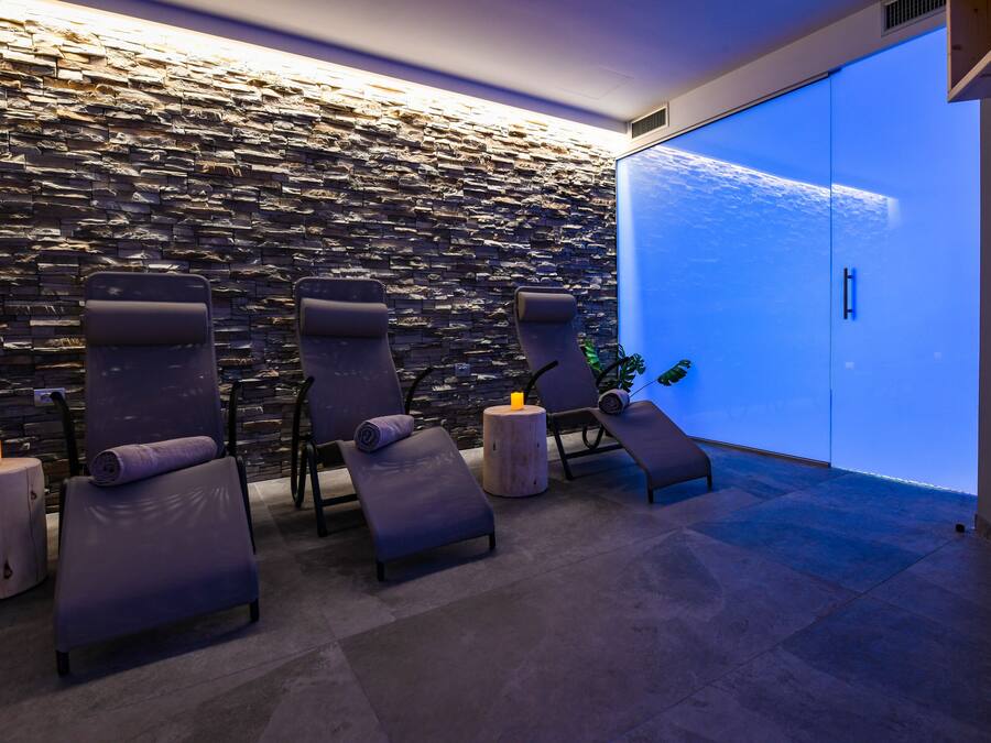 Uma área de spa com paredes de pedra, cadeiras reclináveis e uma janela ampla.