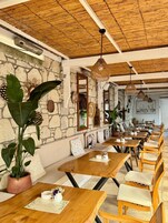 Um restaurante com paredes de pedra, mesas de madeira e luminárias de vime suspensas.