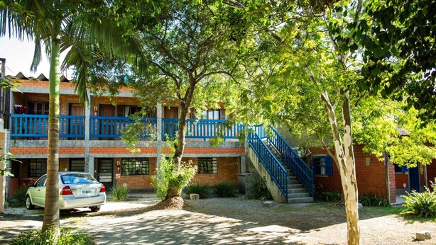 Um edifício de dois andares com escadaria e varanda azuis.