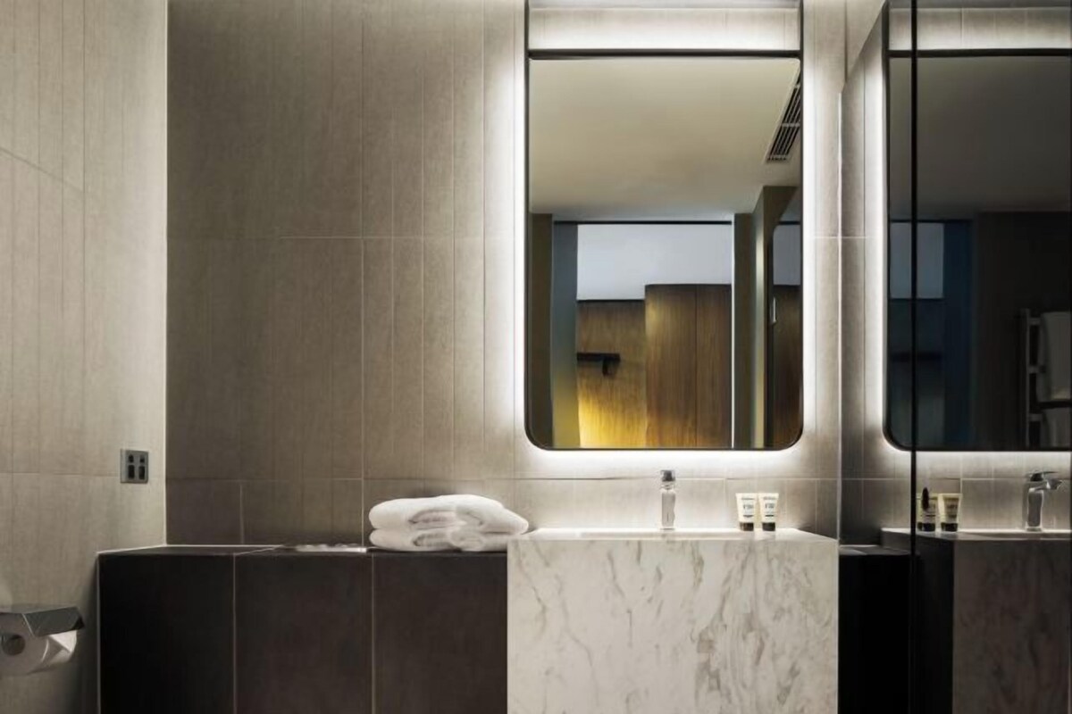 Casa de banho moderna com lavatório de mármore, uma toalha no balcão e um espelho a refletir o espaço.