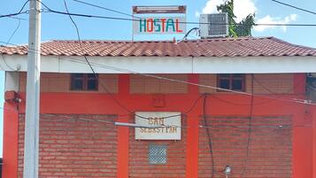 Um hostel com fachada vermelha, uma placa com a inscrição 'SAN SEBASTIAN' e entrada com azulejos.