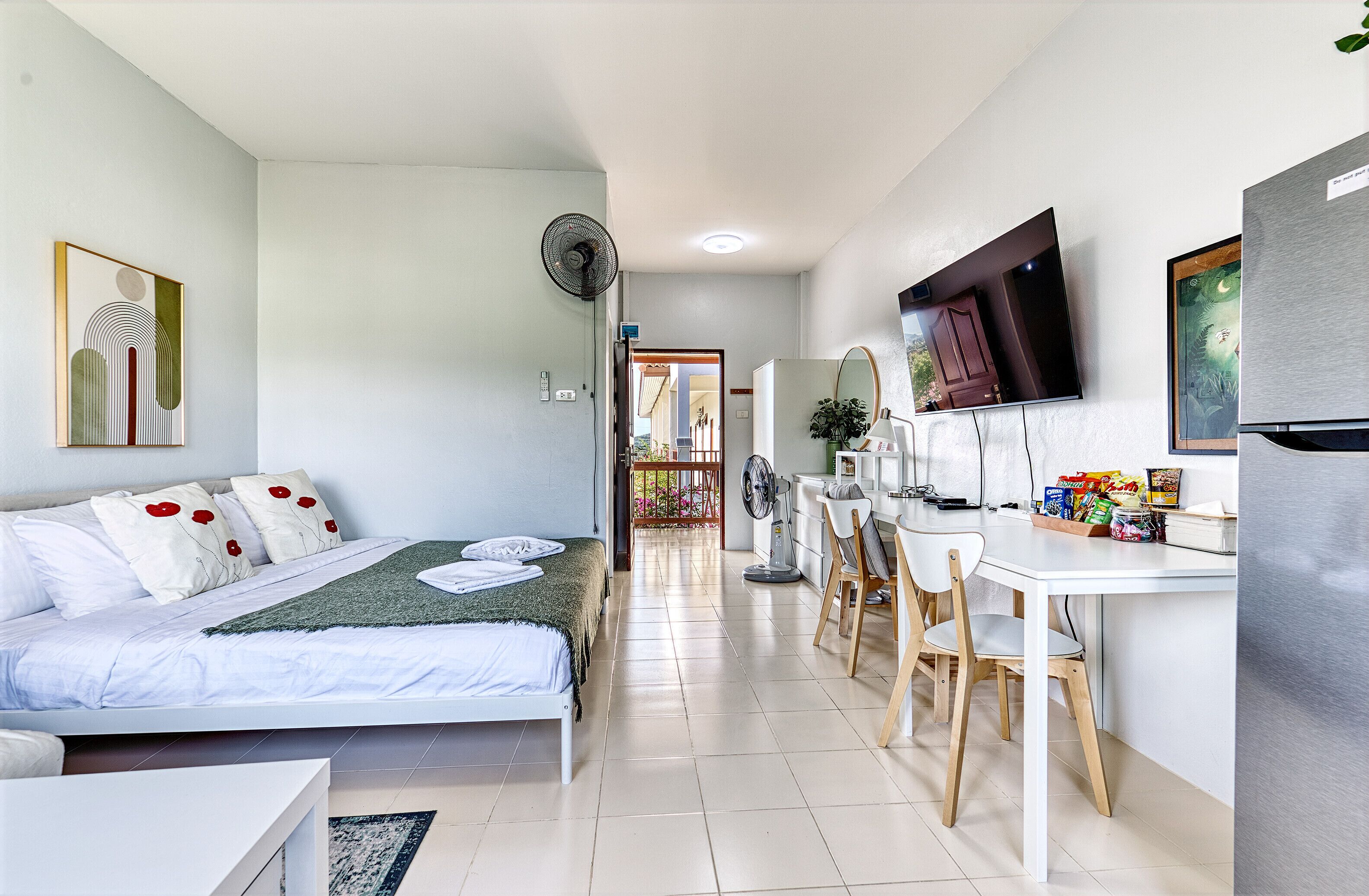 Quarto moderno com cama, mesa de cabeceira e área de trabalho com uma cadeira.