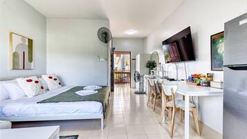 Quarto moderno com cama, mesa de cabeceira e área de trabalho com uma cadeira.