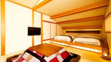 Quarto com cama, televisão de tela plana, mesa de madeira e um vaso decorativo.