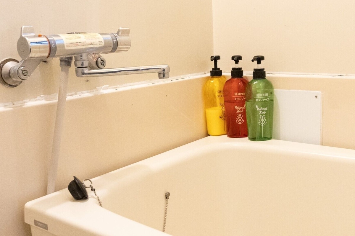 Uma banheira com uma torneira e três frascos de shampoo.