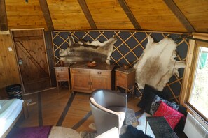 Um interior rústico com paredes de madeira, uma poltrona de couro, um tapete de pele e outro tapete de pele no chão.