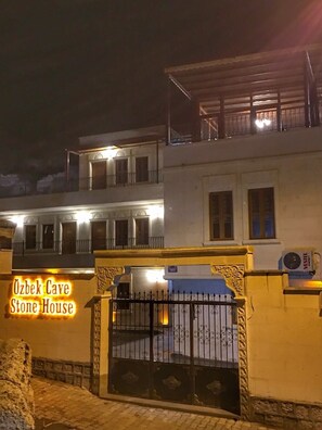 Um edifício com uma placa que diz 'Uzbek Cave Stone House' à noite.