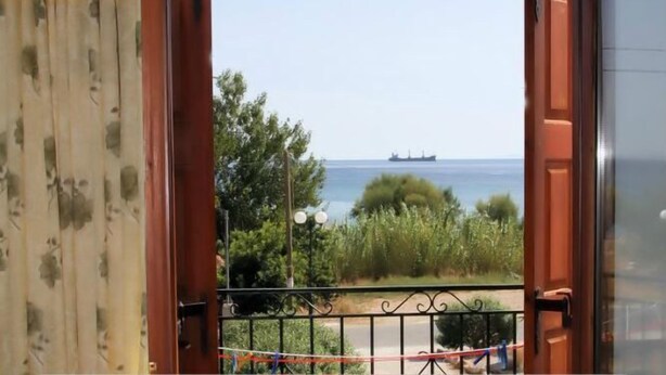 Uma varanda com vista para o mar e um navio ao longe.