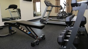 Uma academia com equipamentos de ginástica, incluindo esteiras, um banco e halteres.