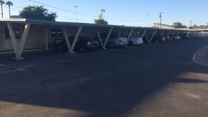 Um estacionamento com uma fileira de carros estacionados sob uma cobertura.