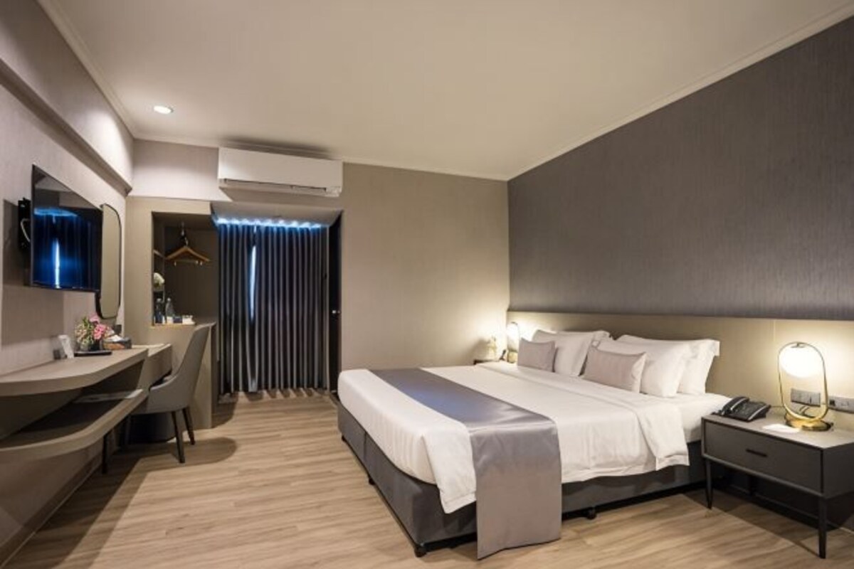 Quarto de hotel moderno com cama, mesa de cabeceira, escrivaninha e cadeira.