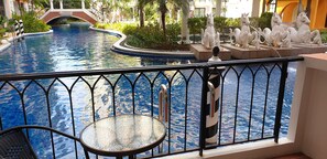 Uma área de piscina com mesa e cadeiras de vidro, cercada por um portão decorativo e estátuas.